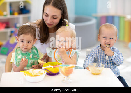 Babies have lunch in creche. Kids eating healthy food in kindergarten ...