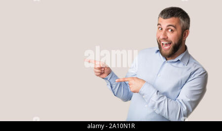 Smiling bearded businessman pointing aside, showing blank copy space ...