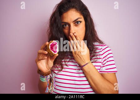 Young beautiful woman holding amethyst gemstone over isolated pink ...