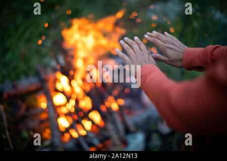 Young camping couple warming hands by campfire at dusk Stock Photo ...