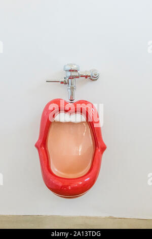 A red lips urinal with white teeth in the men's bathroom at the ...