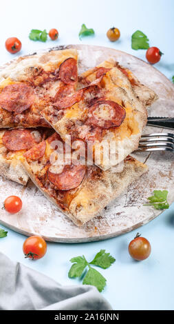 Vertical shot of a delicious sliced pizza with meat and melted cheese ...