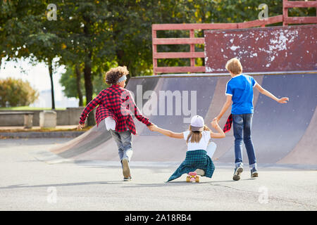 Two girls having fun with a skateboard in the park at sunset Stock ...