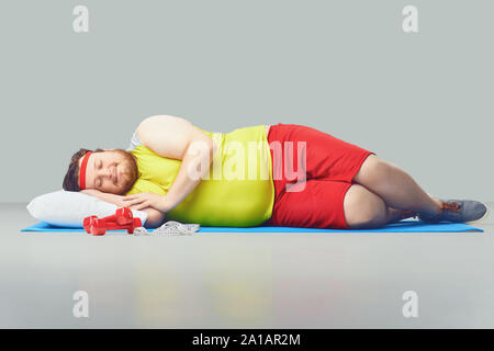 Lazy fat funny man is sleeping on a gray background Stock Photo - Alamy