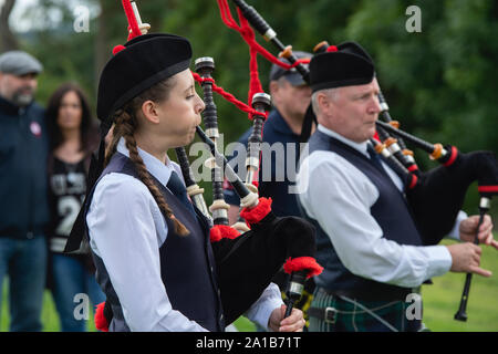 Young girl bagpiper playing bagpipes on street outside in city Glasgow ...