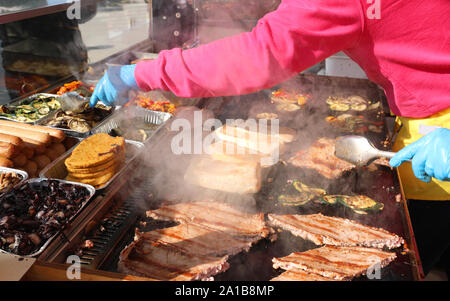 cook with a latex glove while cooking sausages in an alfresco street ...