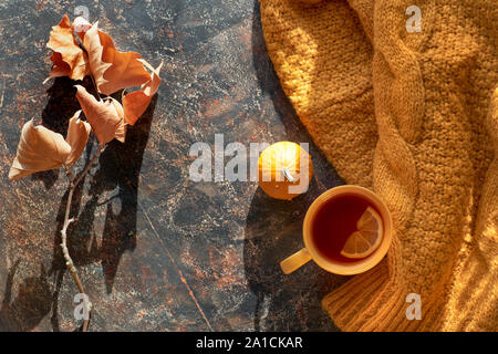 Autumn layout with a cup of lemon tea, pumpkins, dried yellow leaves ...