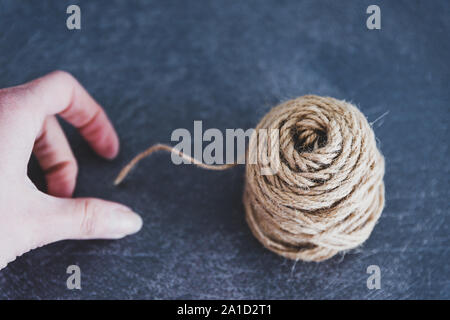 woman's hand untangling ball of thread by pulling string, complex of ...