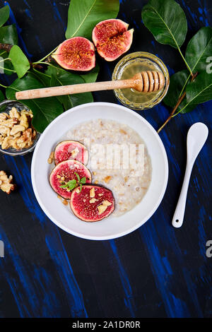 A bowl of porridge with figs slices and walnuts on blue background ...