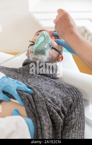 Sick patient in mask lying in hospital ward during medical procedure in ...