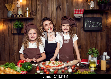 Cute girls in aprons and hats reading recipe book together while ...