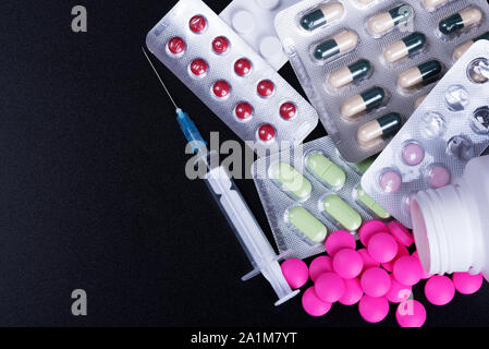 Colorful pills, blister and syringe on a black background Stock Photo ...