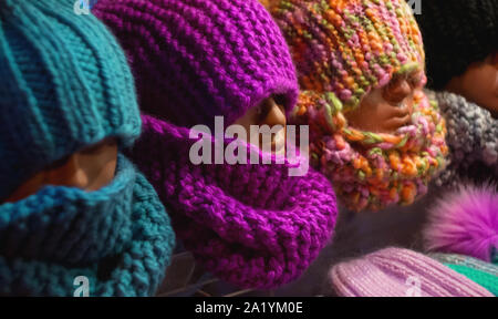 Multi-colored knitted hats and scarves on mannequins. Soft and ...