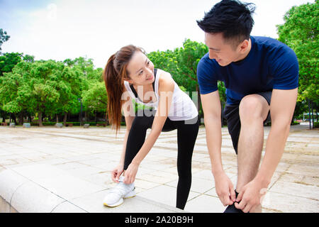 Young hispanic woman tying shoe sitting on floor at street Stock Photo ...