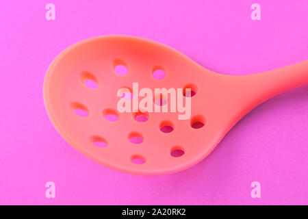 Pink silicone kitchen spatula skimmer in hand on white background ...