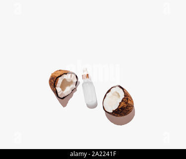 Cracked coconut and bottle of essential oil on beige background Stock ...