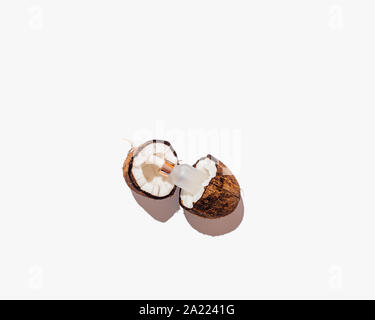 Coconut oil and halves of fresh coconut on a pink background. Hair care ...