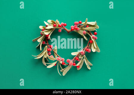 Decorative mistletoe wreath with frosted leaves and red berries shaped ...