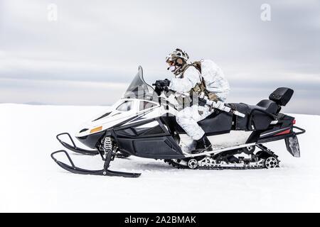 Army soldier in winter camo driving a tracked snowmobile somewhere in ...