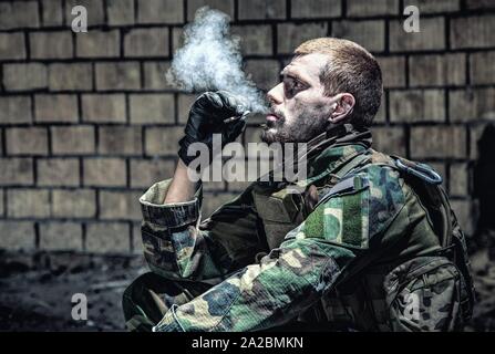 Special forces soldier smoking a cigarette while sitting in a ruined ...