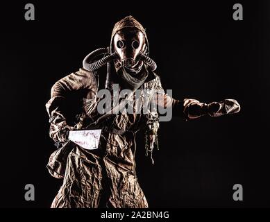 Post apocalyptic creature in ragged clothes and gas mask, armed with a ...
