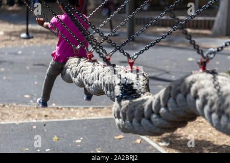 Child riding a rope snake swing in the playground at Battersea Park ...