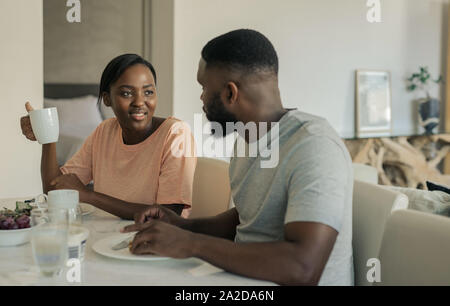 Smiling woman and boyfriend enjoying coffee with sweet dessert together ...