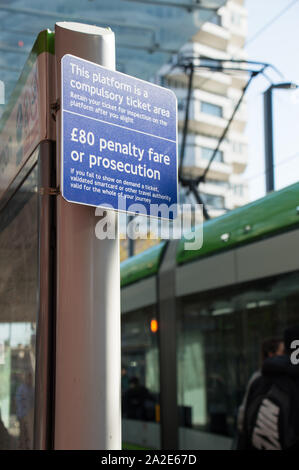 Penalty fare warning sign at TFL operated tram platform with tram on ...