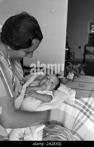 Eine Frau hält ein Baby im Arm und lächelt, Deutschland 1930er Jahre. A ...