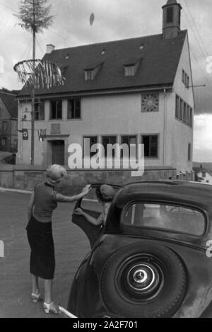 Zwei junge Frauen steigen aus dem Auto, Deutschland 1930er jahre. Two ...