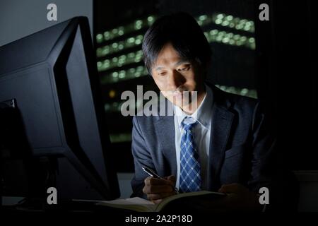 Mature Japanese businessman working overtime at home late at night ...