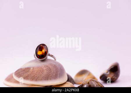 Gemstone ring gift concept. A cinnamon stone ring on seashell on white ...