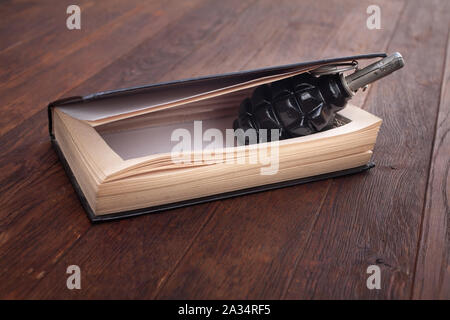 black hand grenade hidden in a book Stock Photo - Alamy