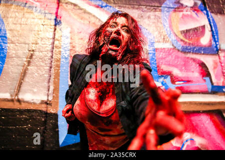A woman wearing a costume seen with fake blood on her face and hand as ...