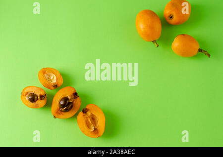 Halves of a Loquat fruits on a bright green background with a space for ...