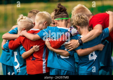 Youth sports coach witch children on soccer field. Kids huddling before ...
