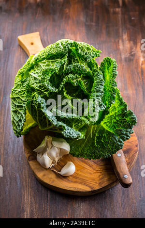 Fresh ripe Savoy cabbage and knife placed on wooden table in rustic ...