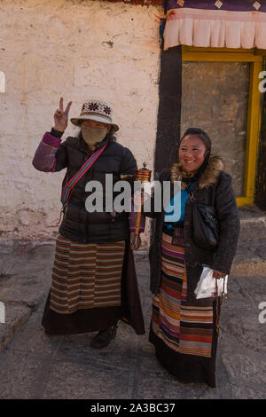 Young Tibetan woman pilgrim spinning prayer wheels outside Mani ...