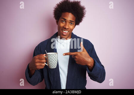 Afro american man wearing pajama drinking coffee standing over isolated ...