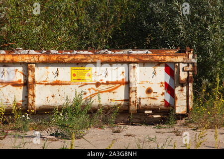 Old rusty settling trough for building rubble standing on a meadow ...