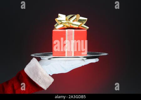 Santa Claus hand holding a wrapped Christmas present Stock Photo - Alamy