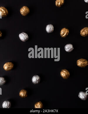 Painted golden and silver walnuts on wooden plate on black background ...