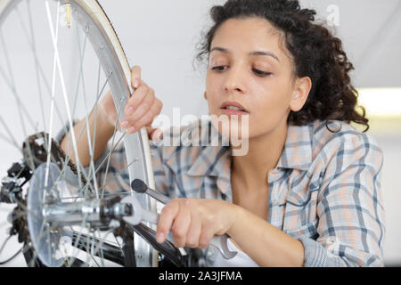 beautiful woman tightening bicycle wheel screws in the garage Stock ...
