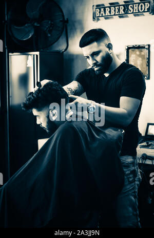 Trendy, handsome, millennial barber, creates a hip haircut for young ...