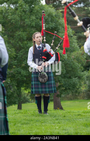 Young girl bagpiper playing bagpipes on street outside in city Glasgow ...