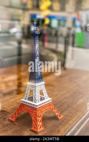 A small-scale model of the eiffel tower standing on a map of Paris ...