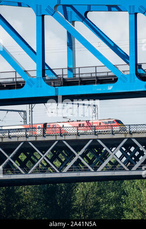 Bright red railway bridge crossing a river valley surrounded by fresh ...