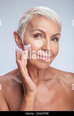 Kind blonde woman keeping smile on her face Stock Photo - Alamy