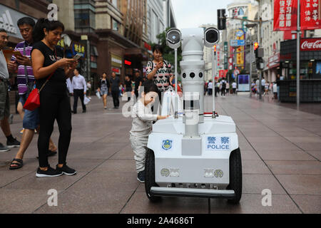 A child plays with the robot patrolman on Nanjing East Road in Shanghai ...