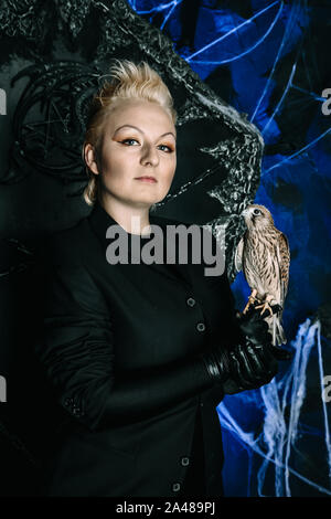 Photo of a female witch queen holding bird and sitting on a gothic ...